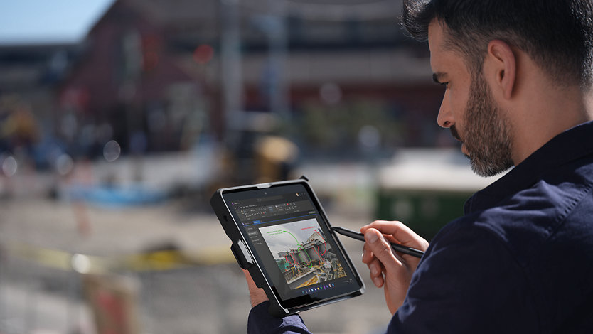 Adult male in the field holding a Surface Go 3 in tablet mode in a Designed for Surface ruggedized case while inking with a Surface Pen on Microsoft OneNote.