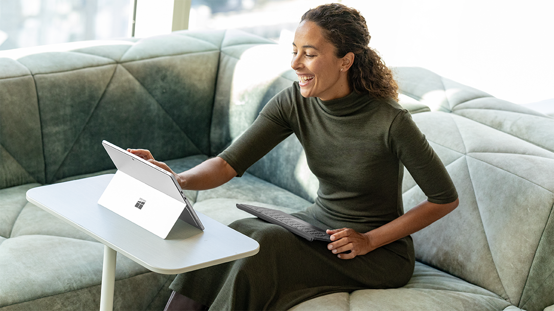 A woman sitting on a couch with a Surface Pro learning how to customize Microsoft Edge browser tab pages